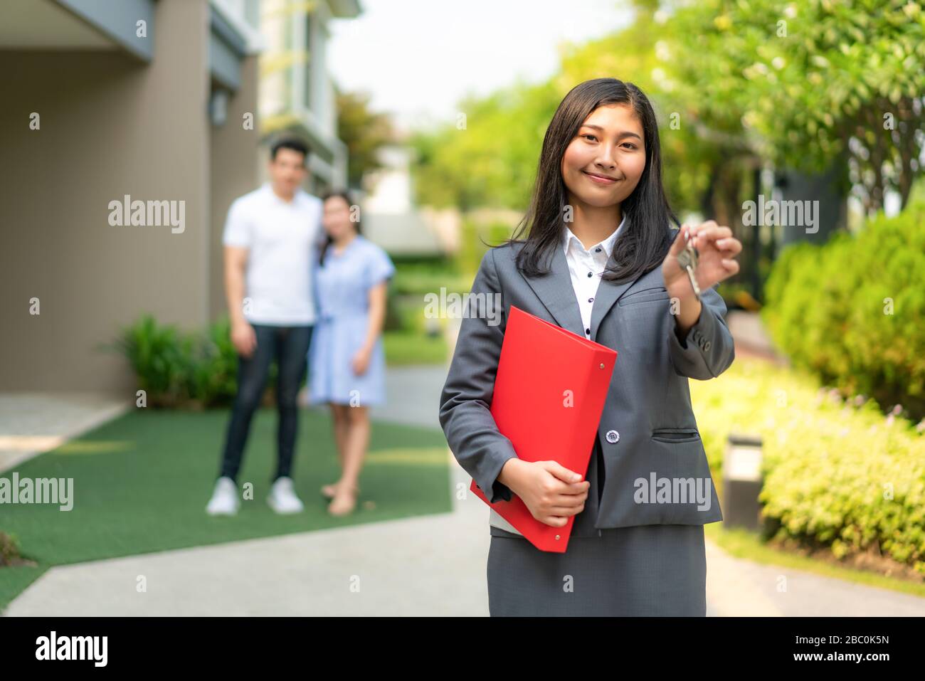 Asian Real Estate Agent Or Realtor Woman Smiling And Holding Red File With Showing House Key