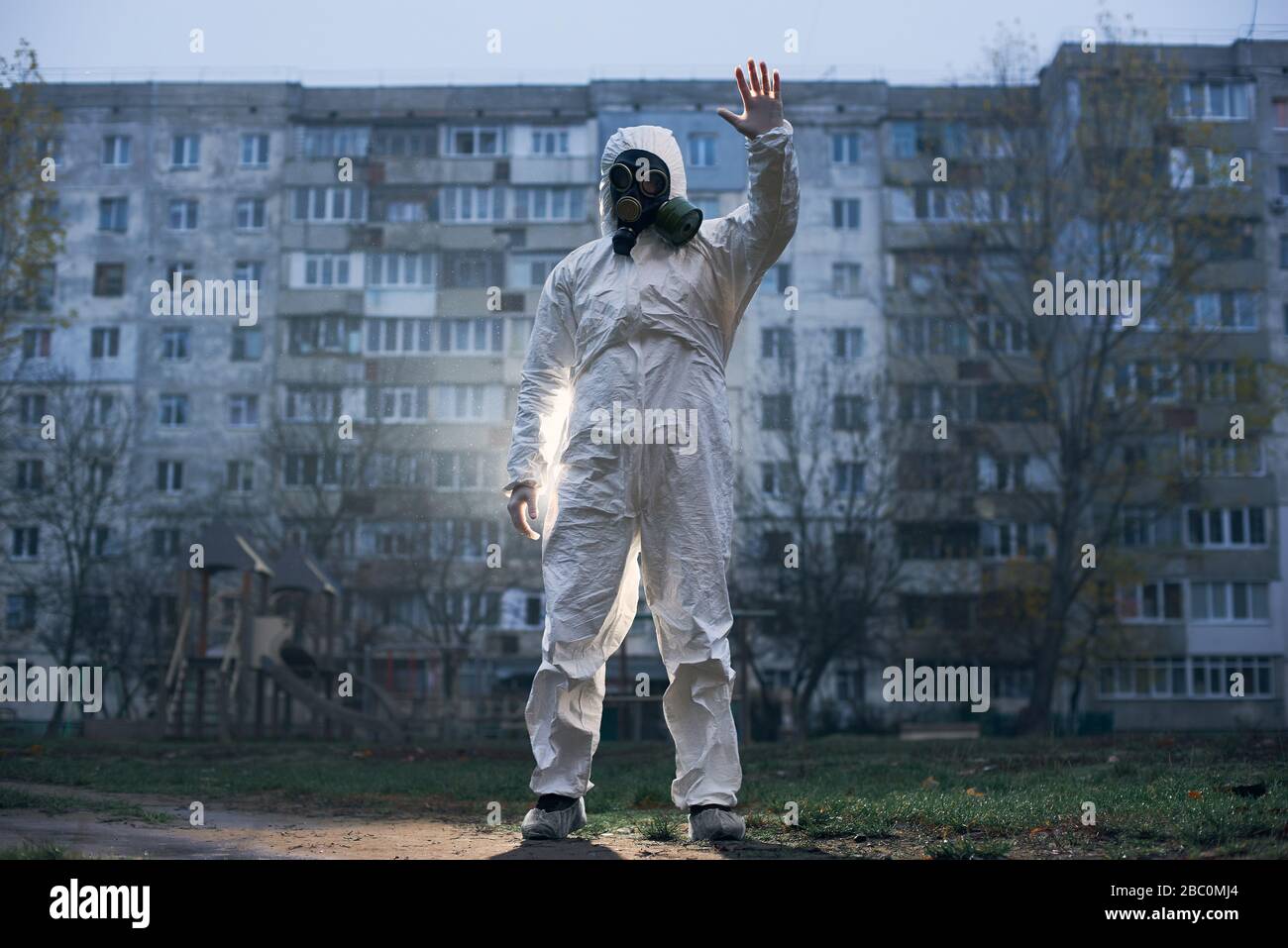 Male ecologist standing in front of high block of flats, showing stop ...