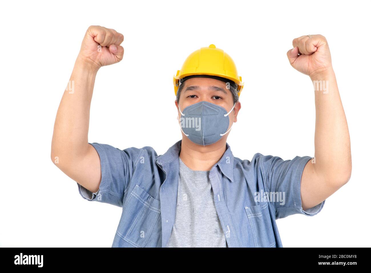 Male worker wearing a helmet and face mask and looking at camera in ...