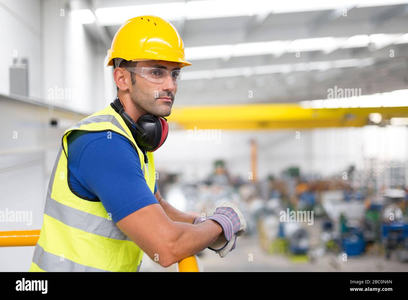 Serious male supervisors leaning on platform railing in factory Stock ...
