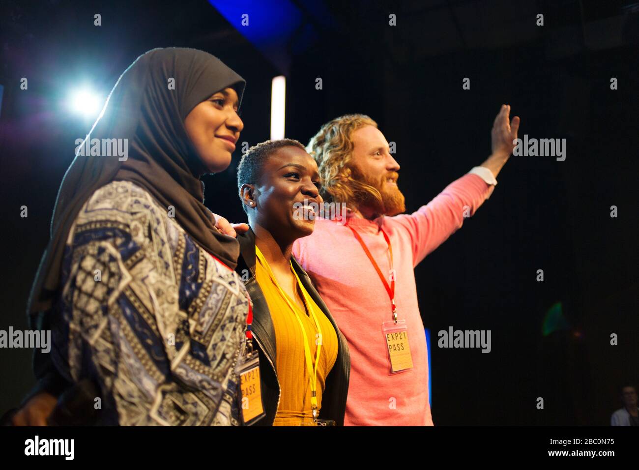 Smiling speakers waving on stage Stock Photo - Alamy