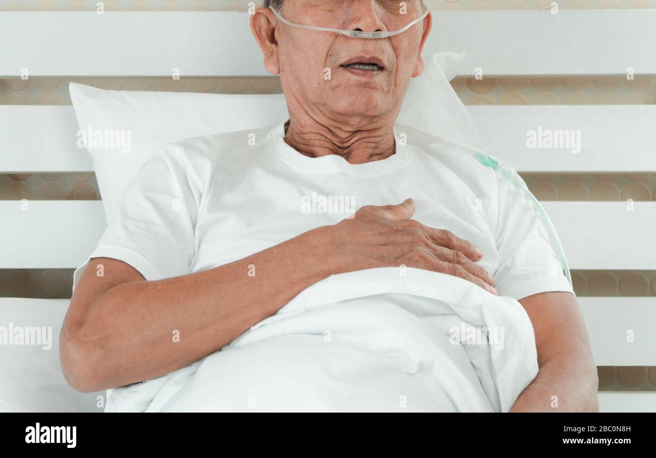 Sad senior man lying on the hospital bed and with a nasal breathing ...