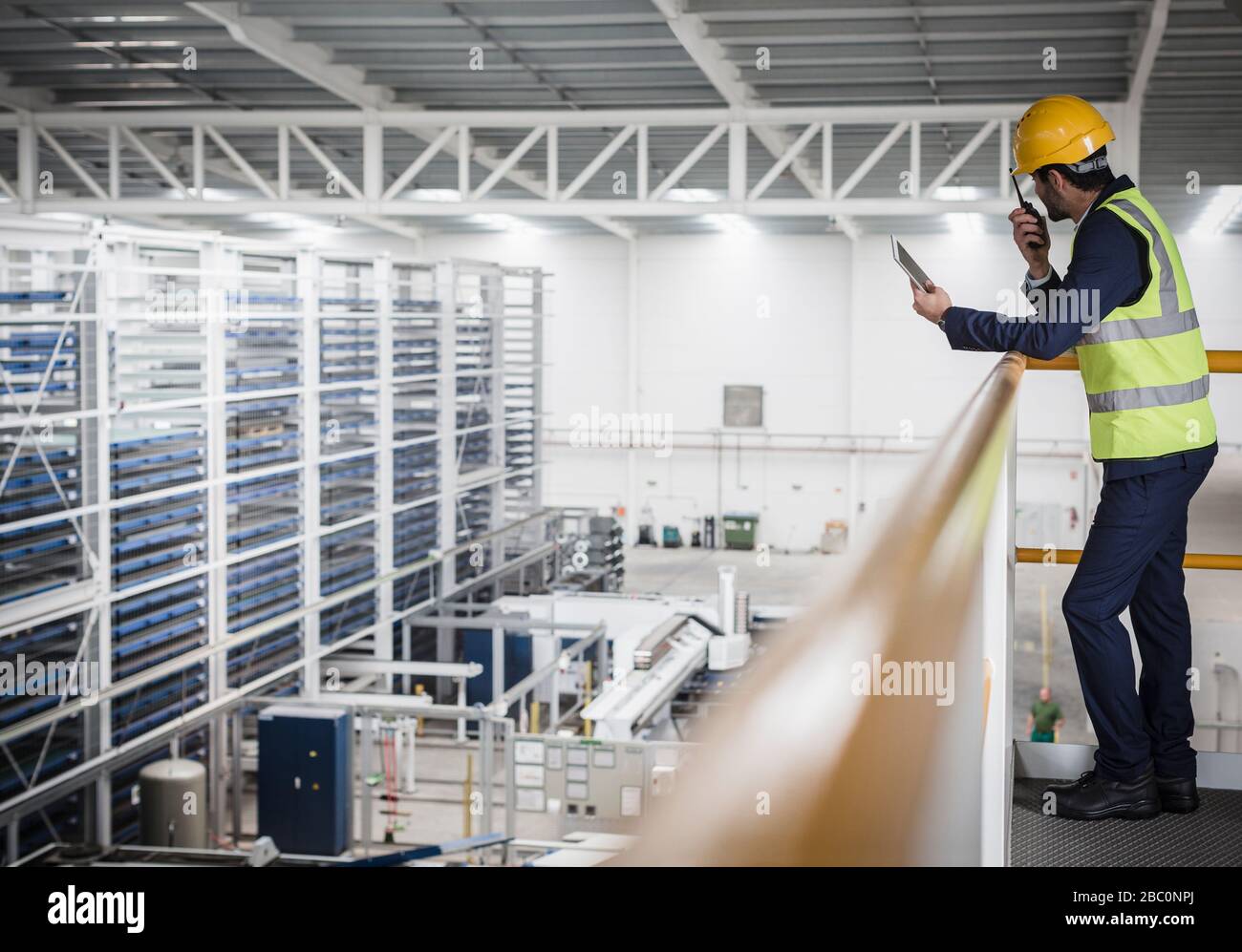 Male supervisor with digital tablet talking, using walkie-talkie on ...