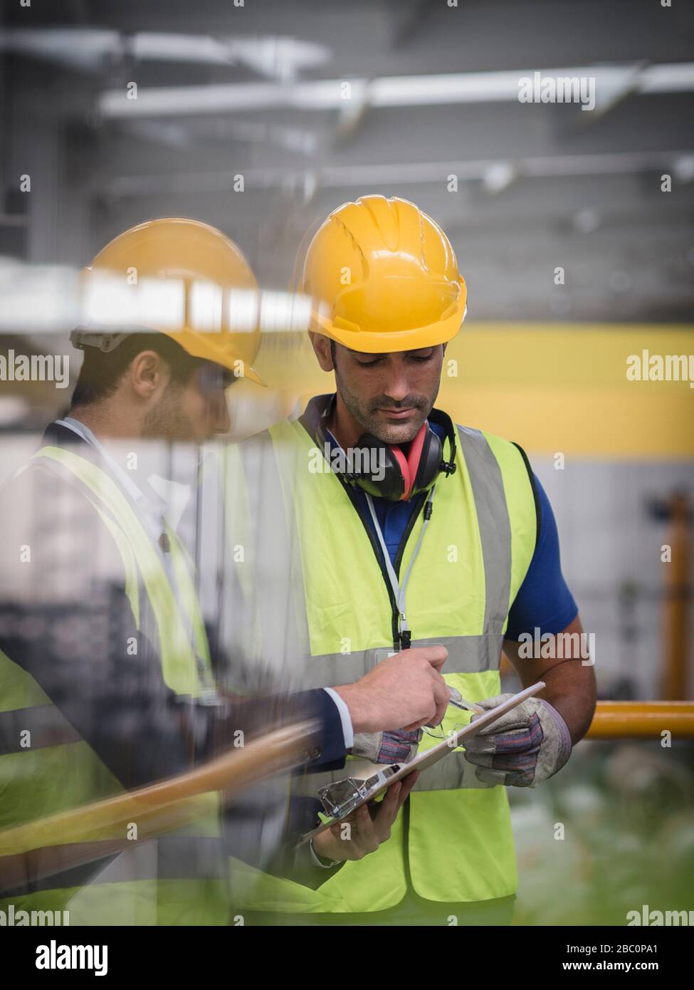 Male supervisor and worker with clipboard talking in factory Stock ...
