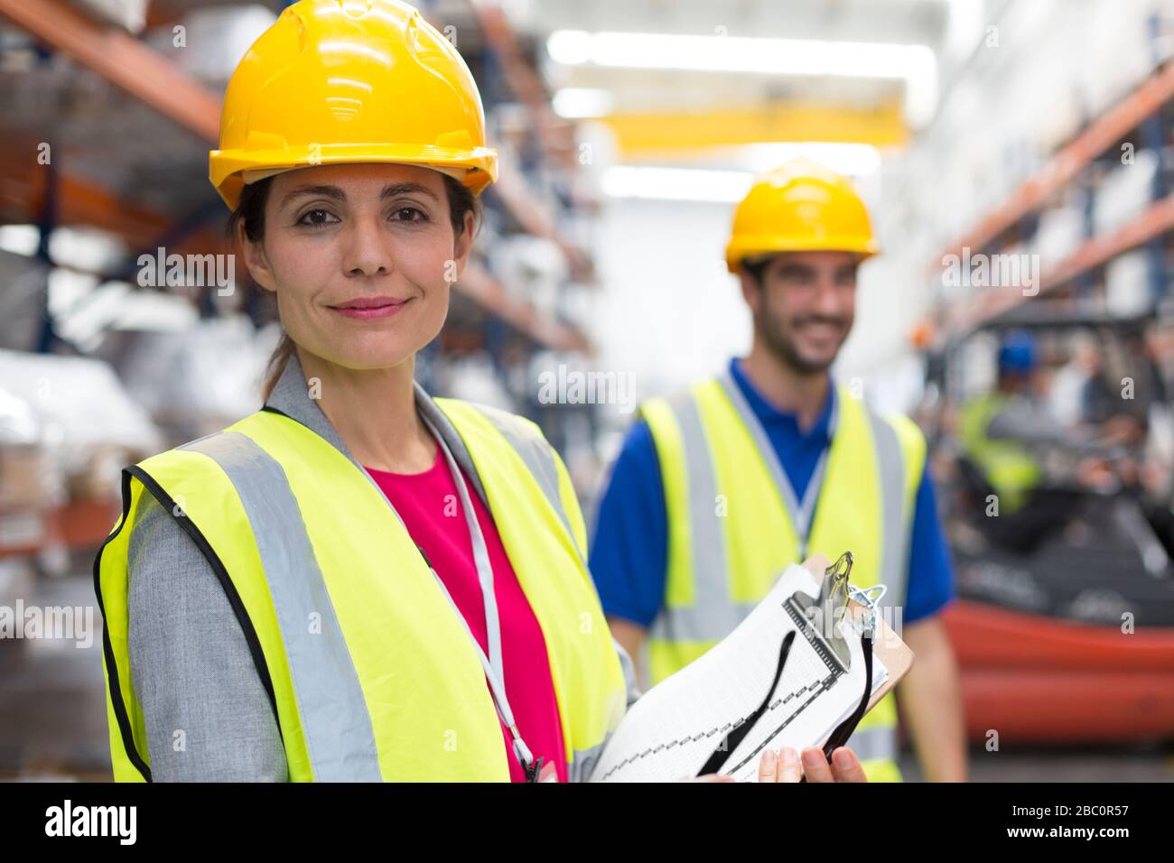 Portrait confident female supervisor with clipboard in warehouse Stock ...