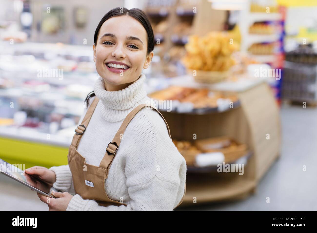 Portrait happy, confident female grocer with digital tablet working in ...