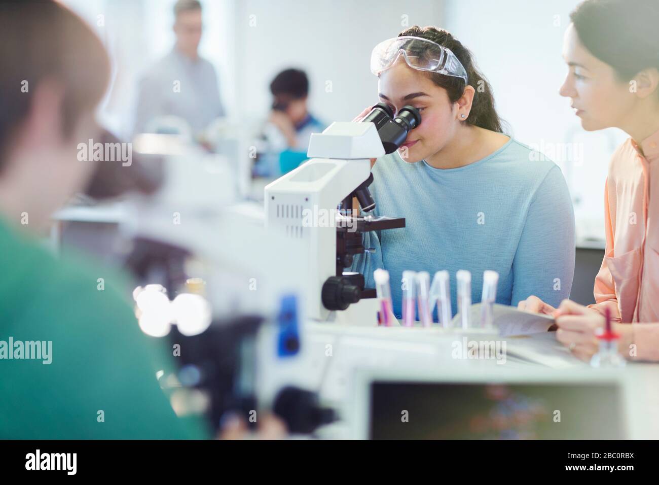 Girl students using microscope, conducting scientific experiment in ...