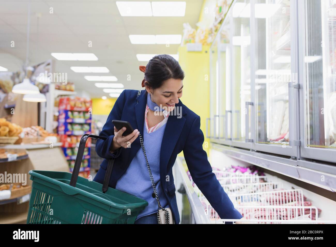 Woman with smart phone shopping in supermarket Stock Photo - Alamy