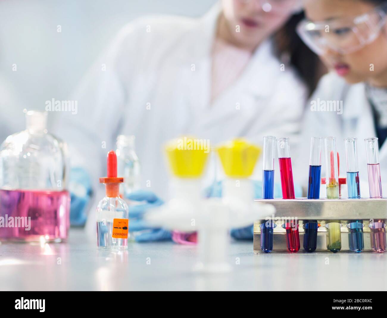 Girl students conducting scientific experiment behind test tubes and ...