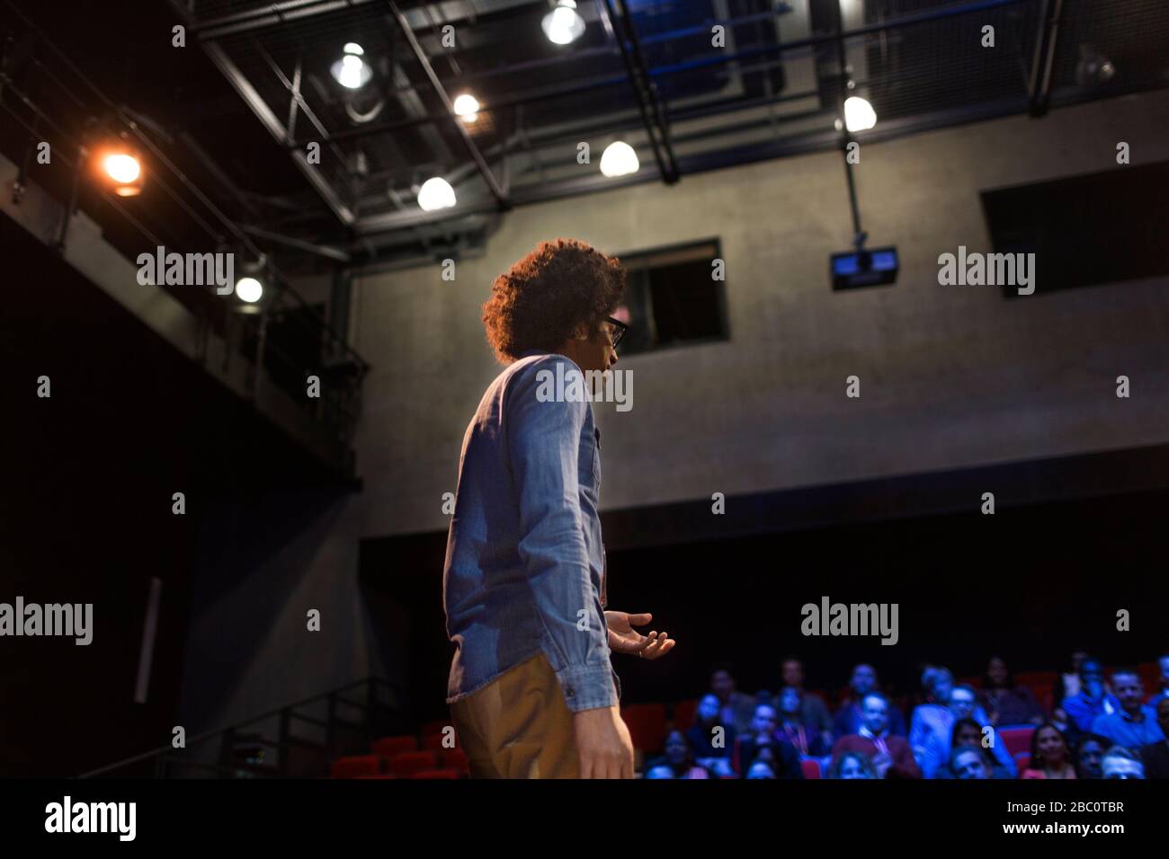 Male speaker on stage talking to audience Stock Photo - Alamy