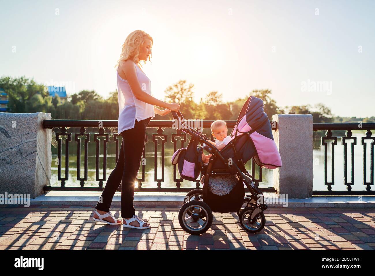 Mothers day. Young mother walking in spring park with infant in baby ...