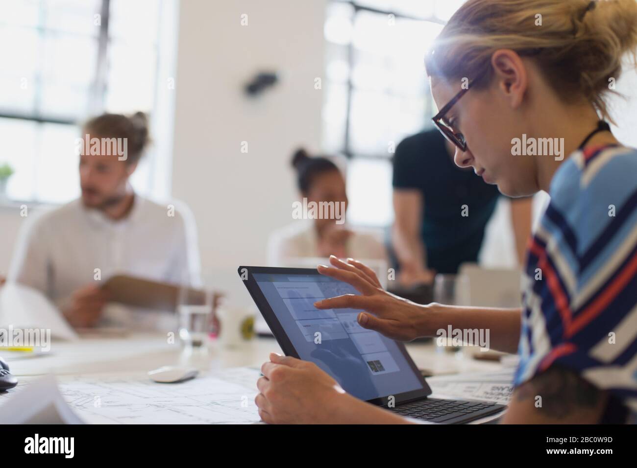 Female architect using touch screen laptop in conference room meeting ...