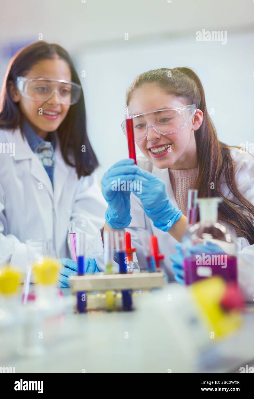 Smiling girl students examining liquid in test tube, conducting ...