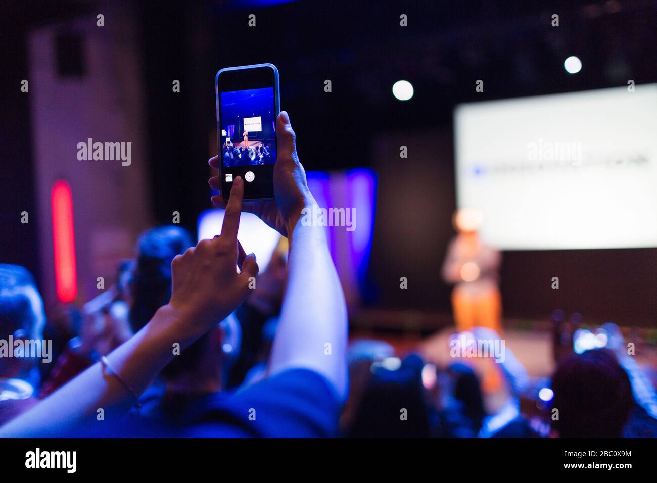 Woman with camera phone photographing conference presentation Stock ...