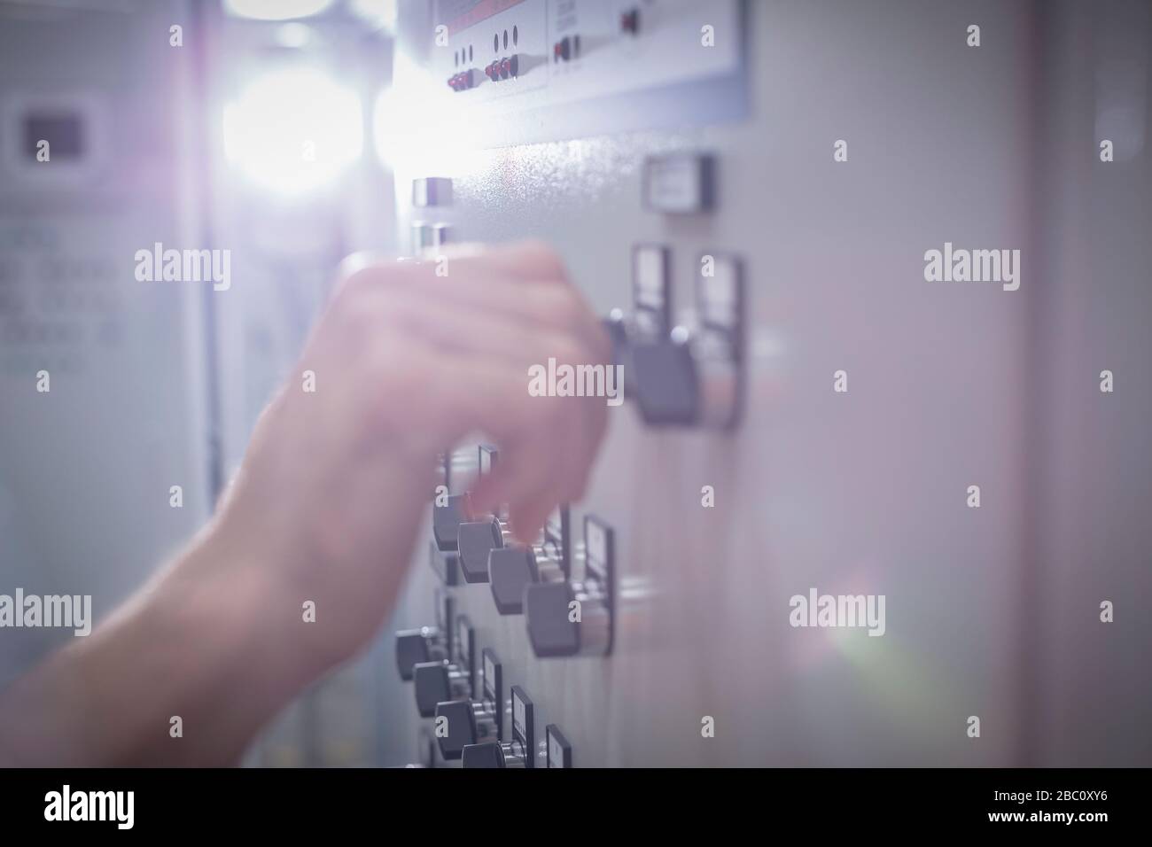 Close up hand adjusting knob, operating machinery at control panel in ...