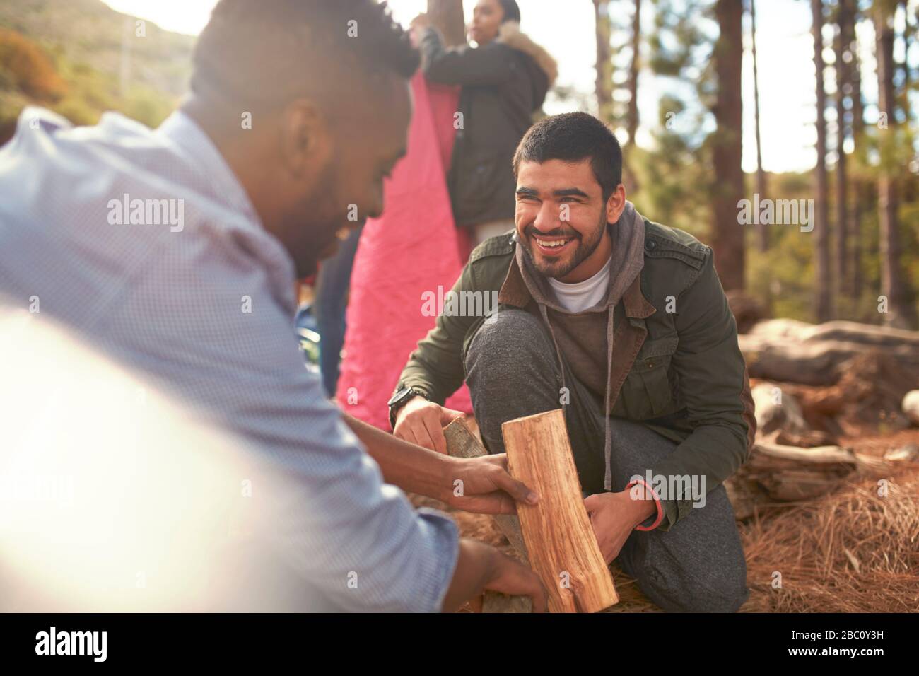 Young men friends building campfire at campsite Stock Photo - Alamy