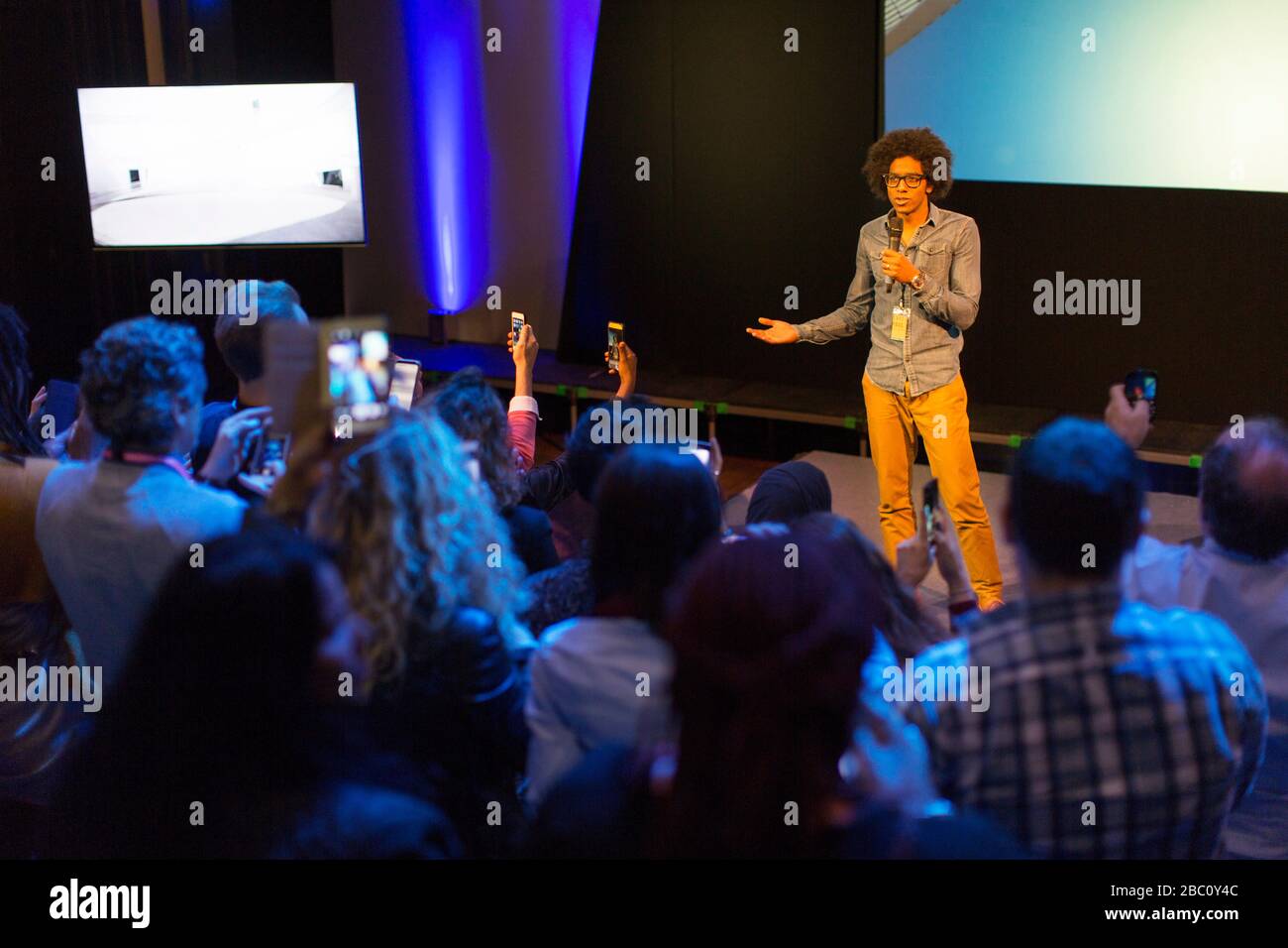 Male speaker with microphone talking to audience Stock Photo - Alamy