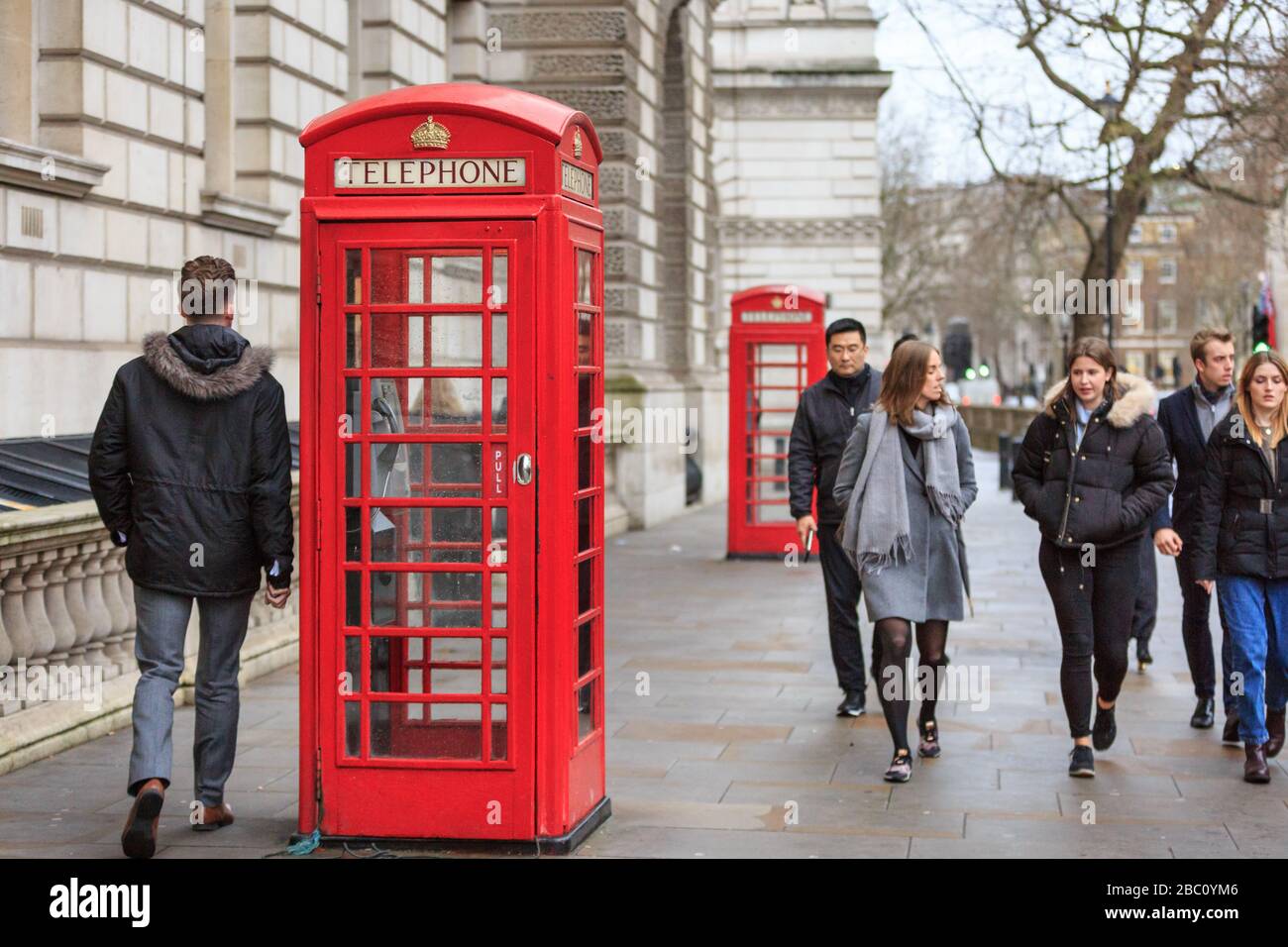 Iconic British Telephone box, people walking past red telephone boxes ...