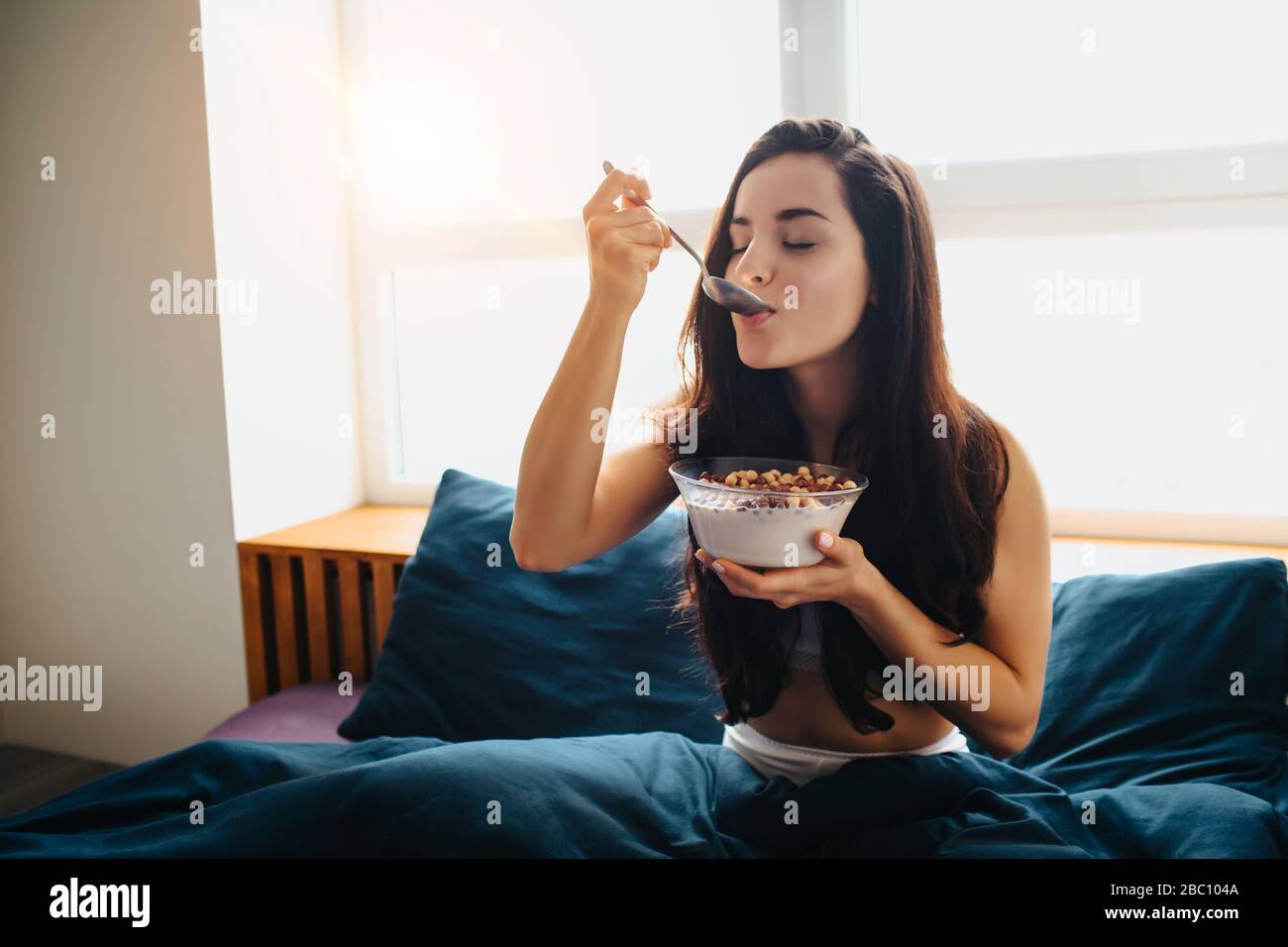 Young beautiful woman in morning bed at home. Eating breakfast ...