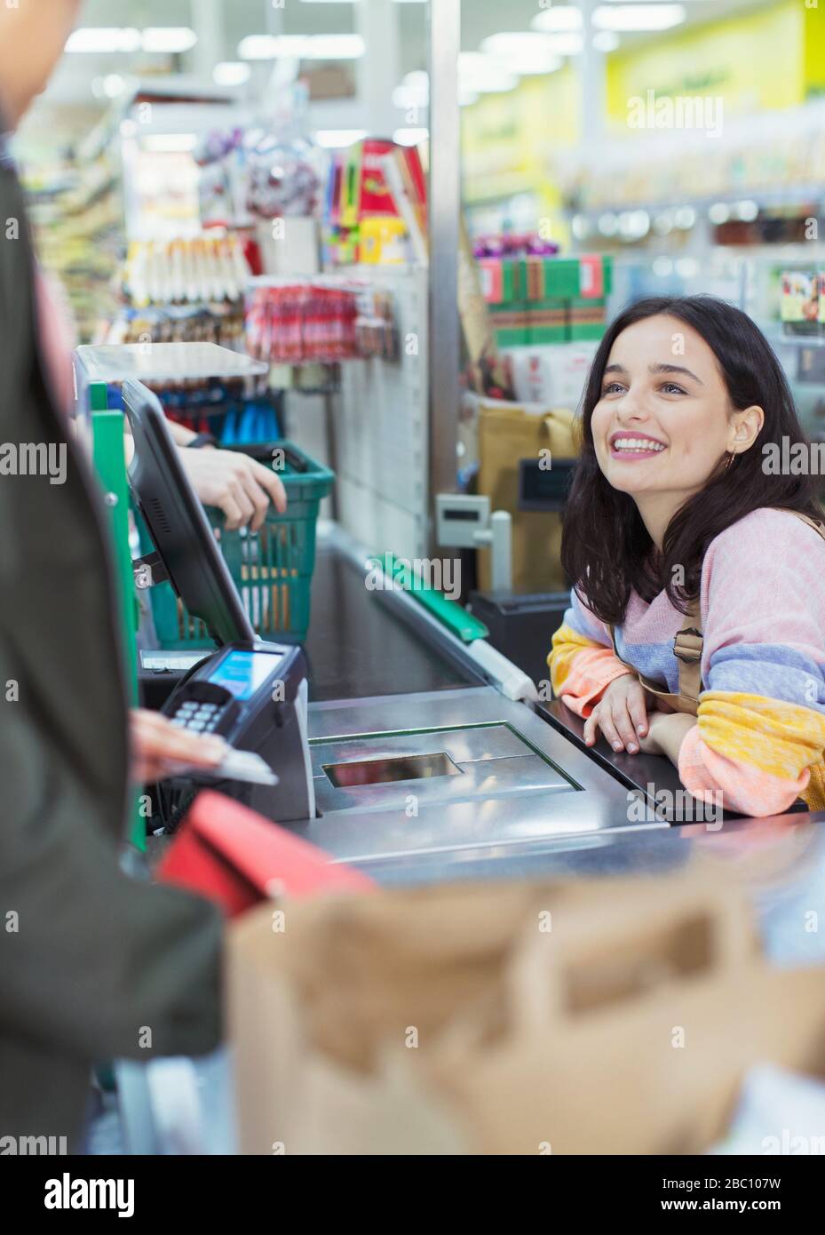 Friendly female cashier helping customer at supermarket checkout Stock ...