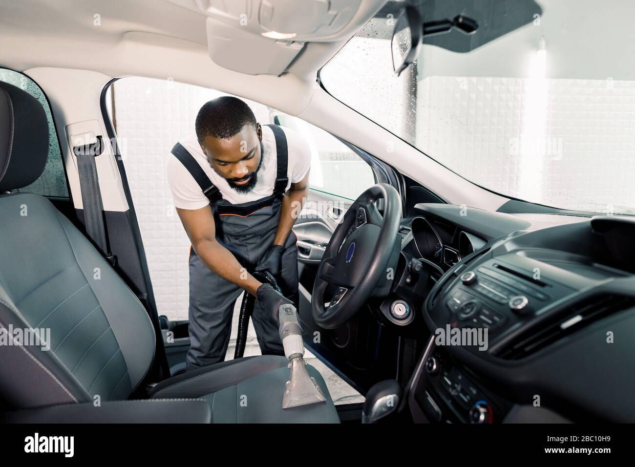 Car interior detailing concept. Young African American man in uniform ...
