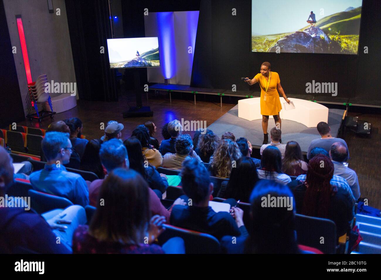 Female speaker on stage answering audience questions Stock Photo - Alamy
