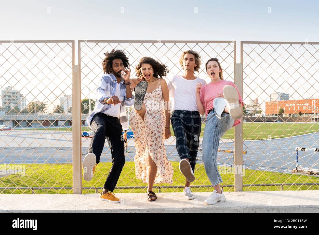 Portrait of happy friends posing at a wire mesh fence Stock Photo - Alamy