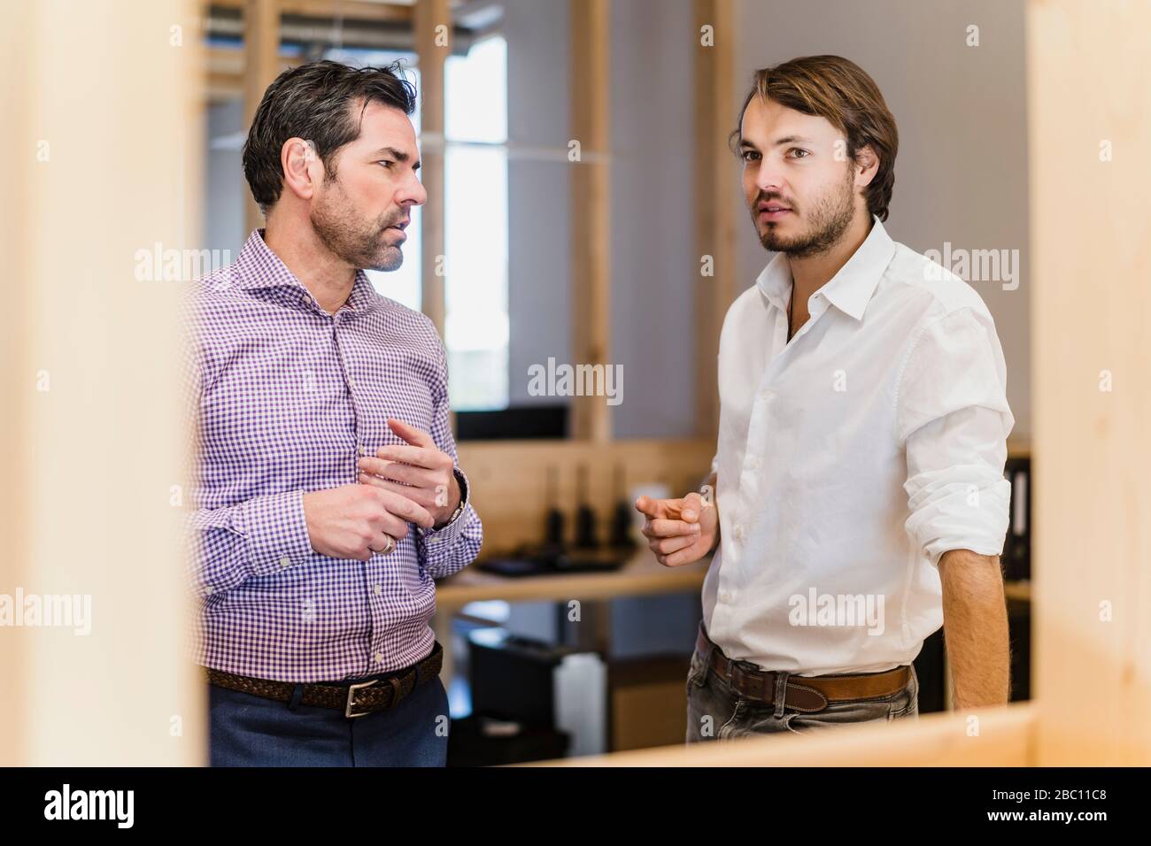 Two businessmen talking in wooden open-plan office Stock Photo - Alamy