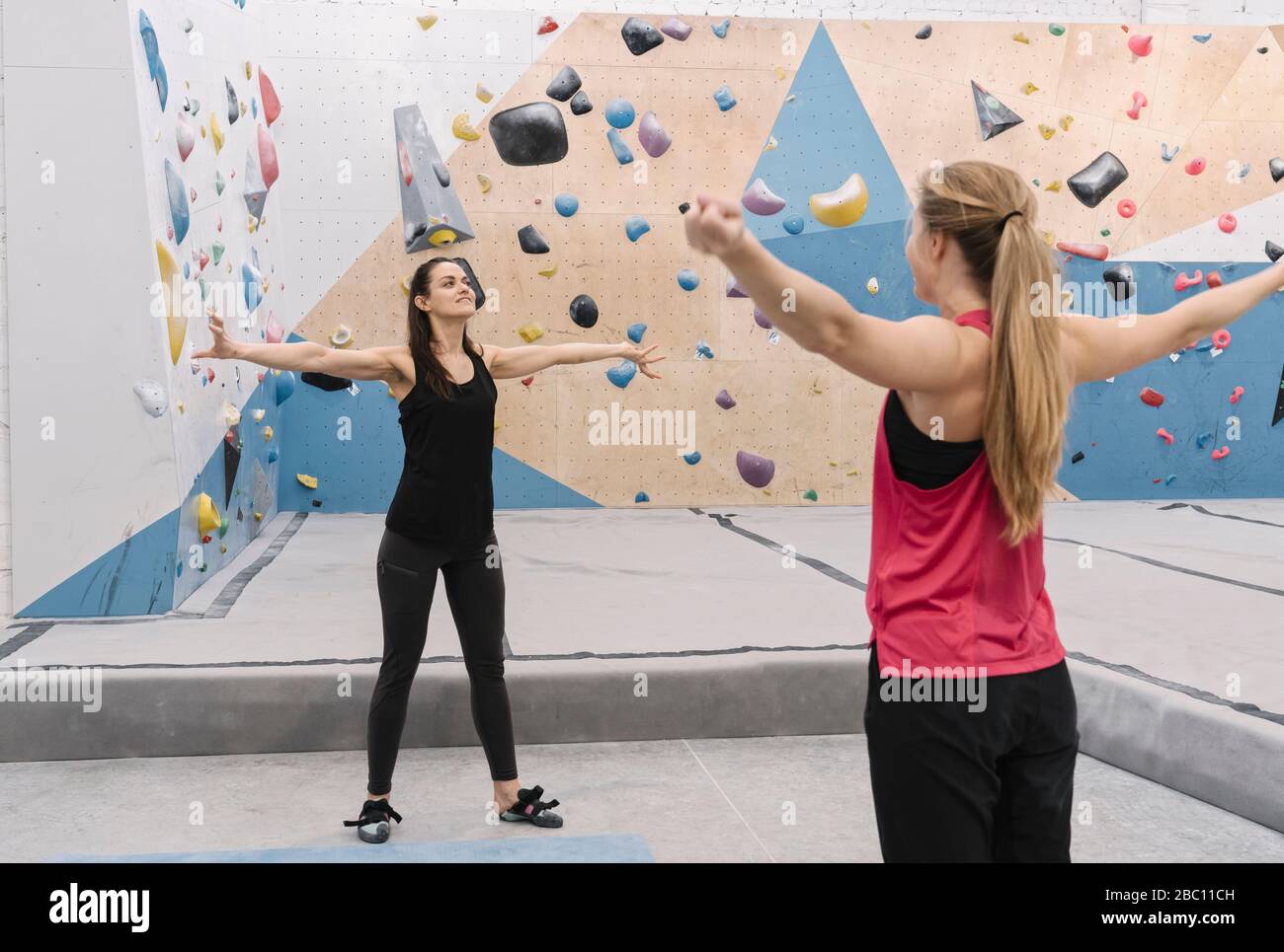 Two women doing stretching exercises before climbing on the wall Stock ...