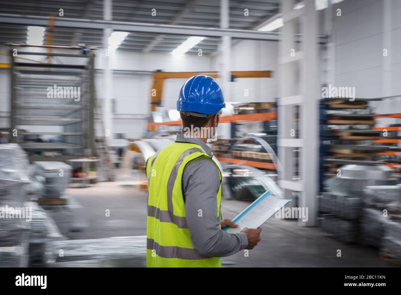 Male supervisor with paperwork walking in warehouse Stock Photo - Alamy