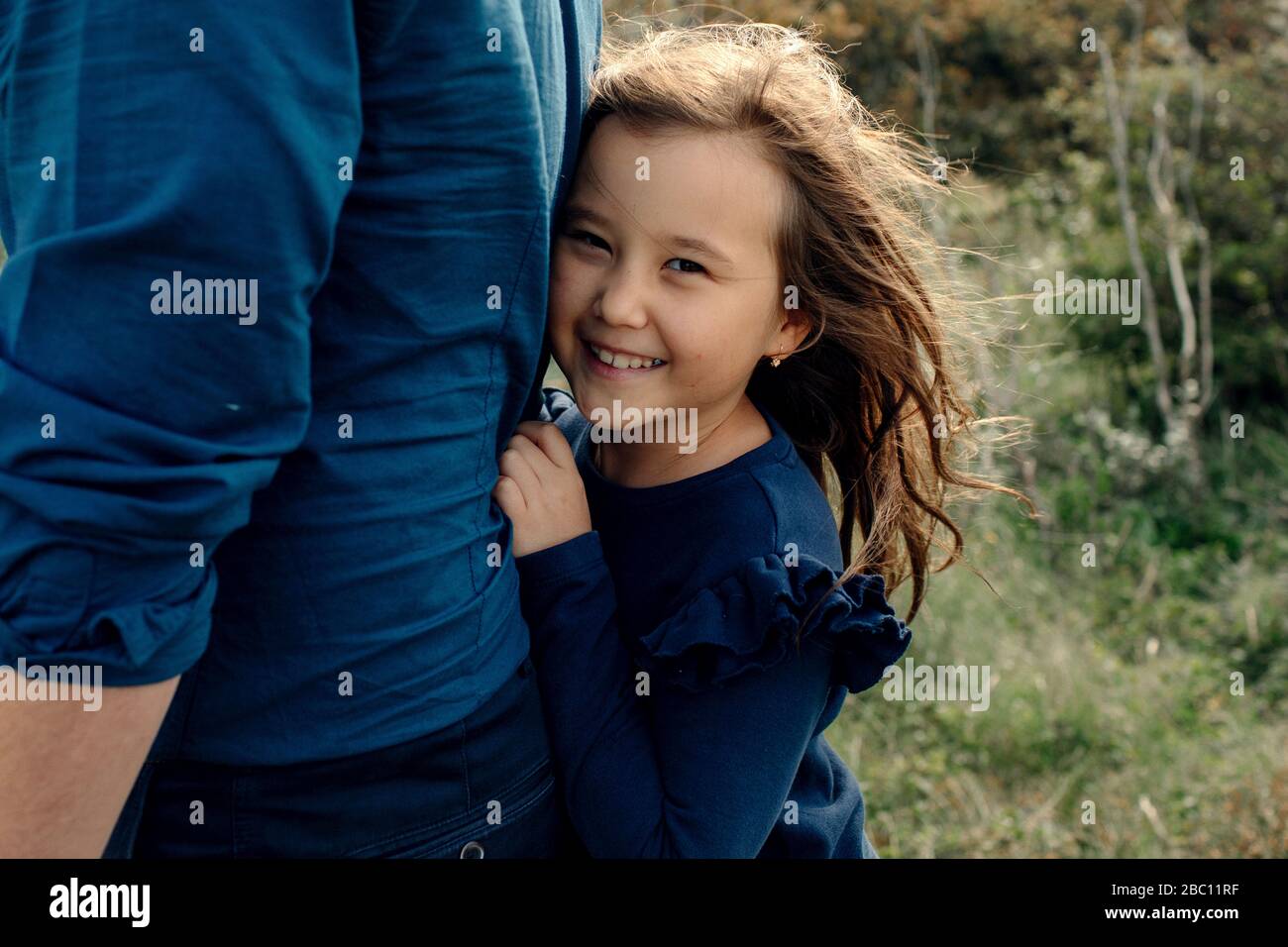 Portrait of laughing little girl hiding behind her father's back Stock ...