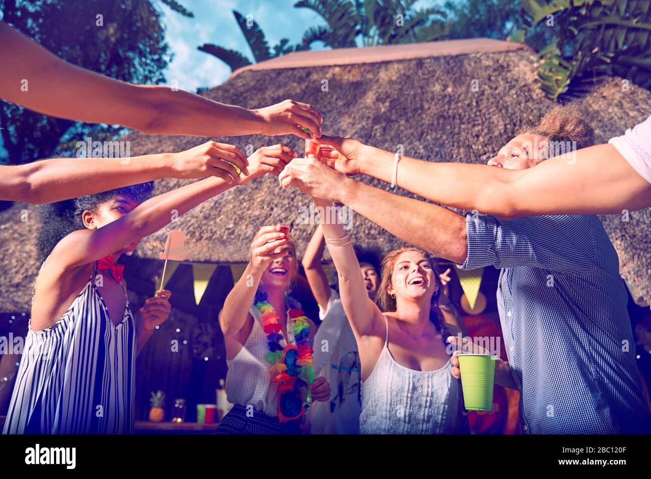 Young friends toasting alcohol in shot glasses at poolside party Stock ...