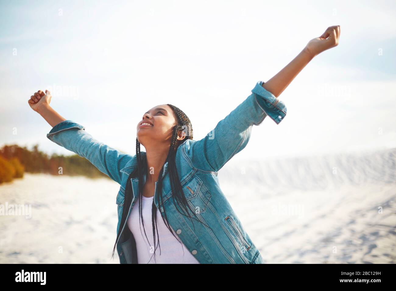 Exuberant young woman with arms outstretched on beach Stock Photo - Alamy