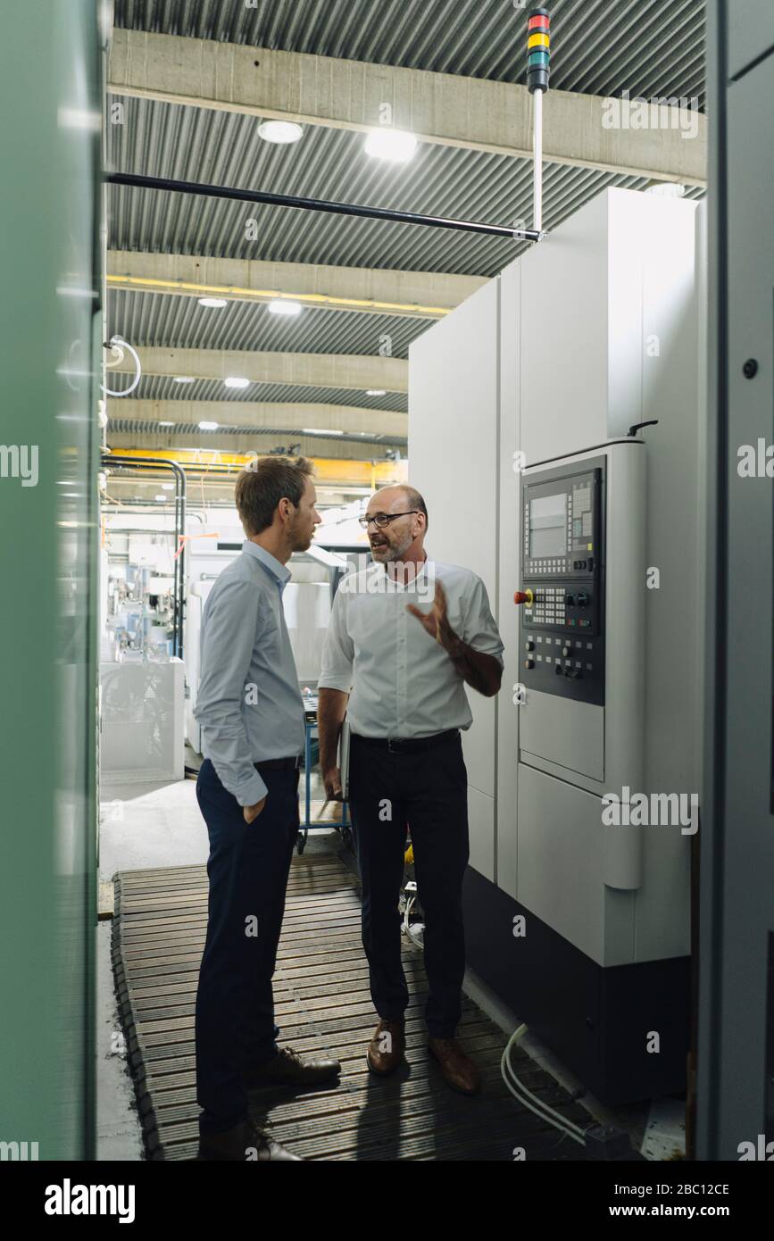 Two men talking in a factory Stock Photo - Alamy