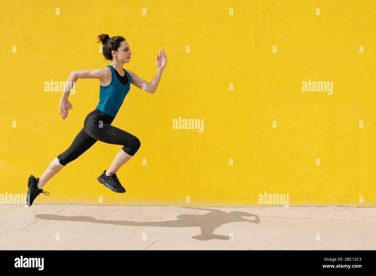 Young woman jogging in front of a yellow wall Stock Photo - Alamy