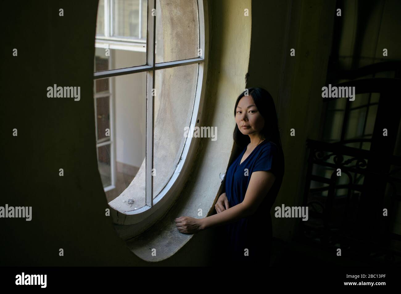 Portrait of woman standing beside window Stock Photo - Alamy