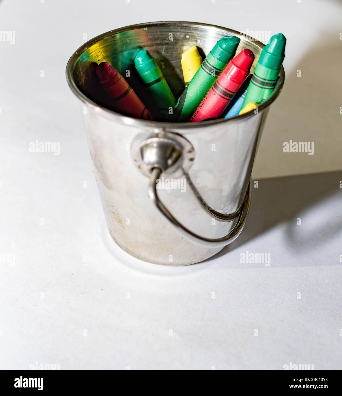 Crayons inside an aluminum bucket closeup shot white background. For ...