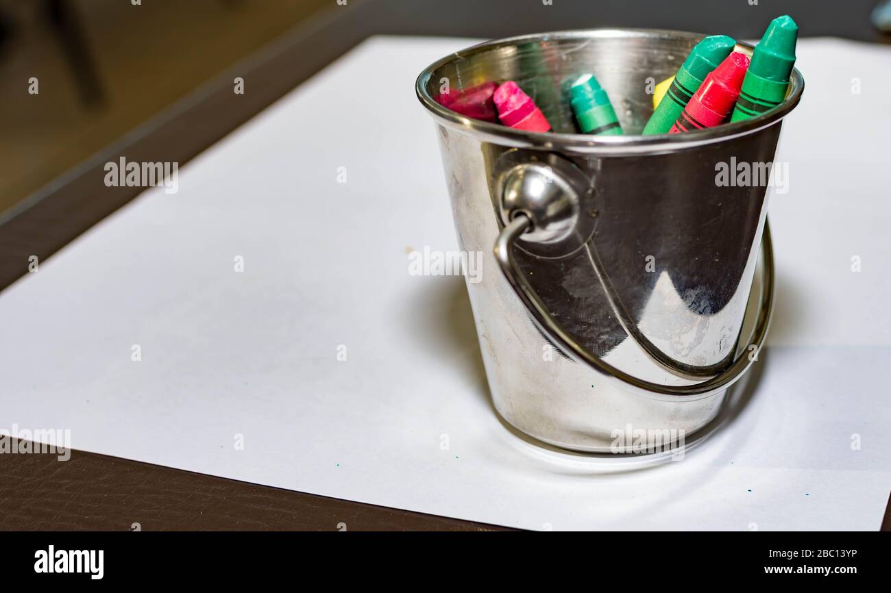 Crayons inside an aluminum bucket closeup shot white background. For ...