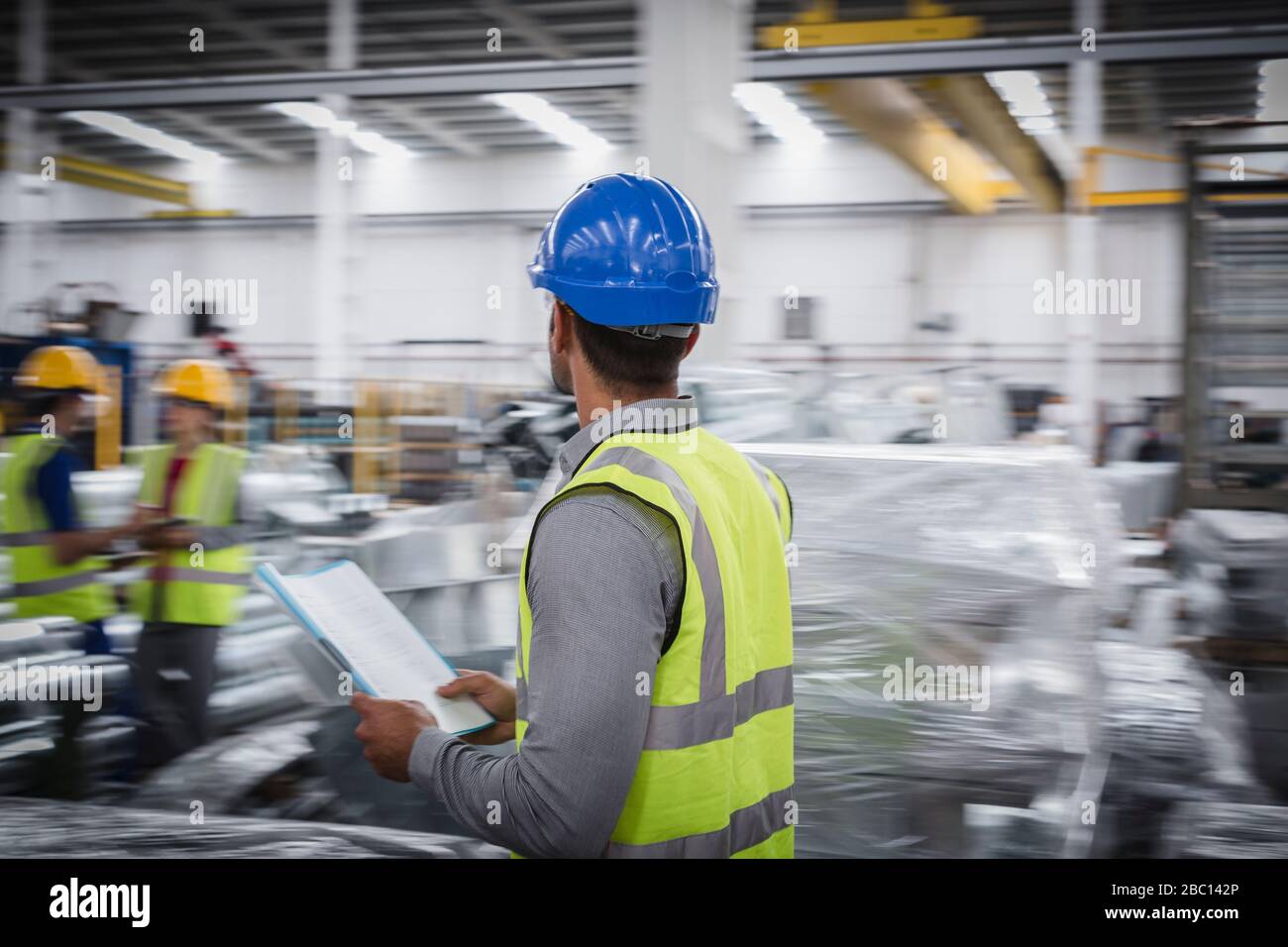 Male supervisor with paperwork walking in steel factory Stock Photo - Alamy