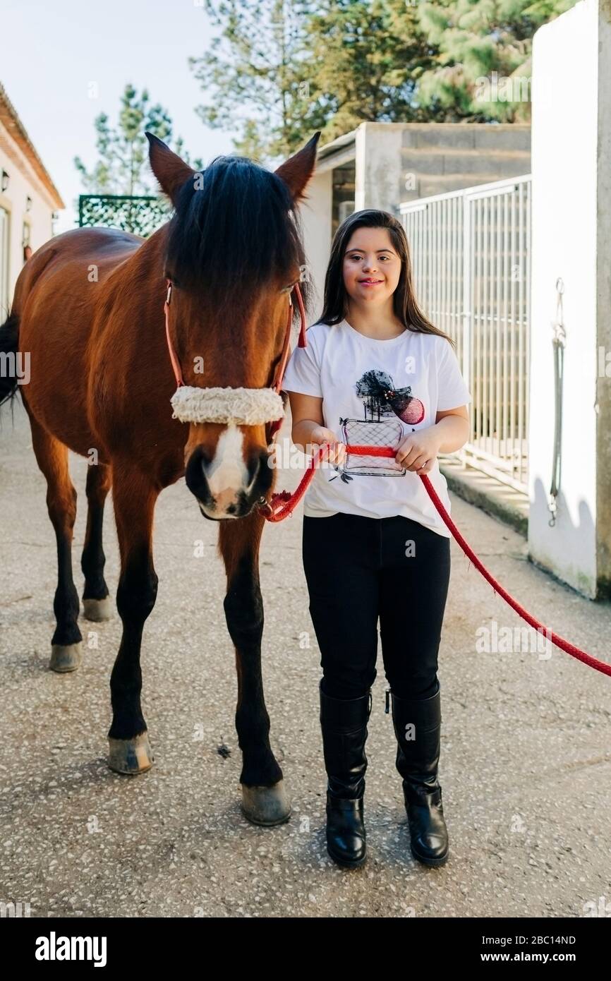 Teenager with down syndrome taking care of horse and preparing horse to ...