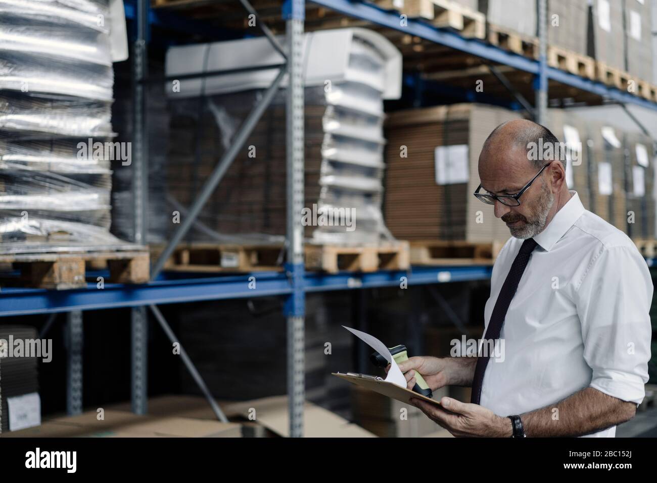 Man with clipboard and scanner in factory warehouse Stock Photo - Alamy