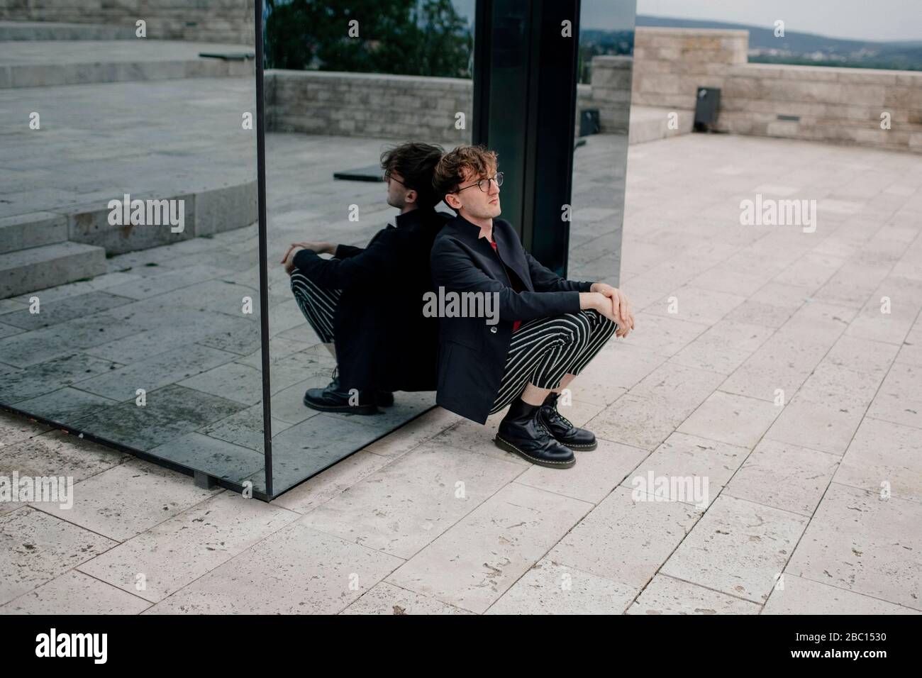 Pensive young man crouching view terrace hi-res stock photography and ...