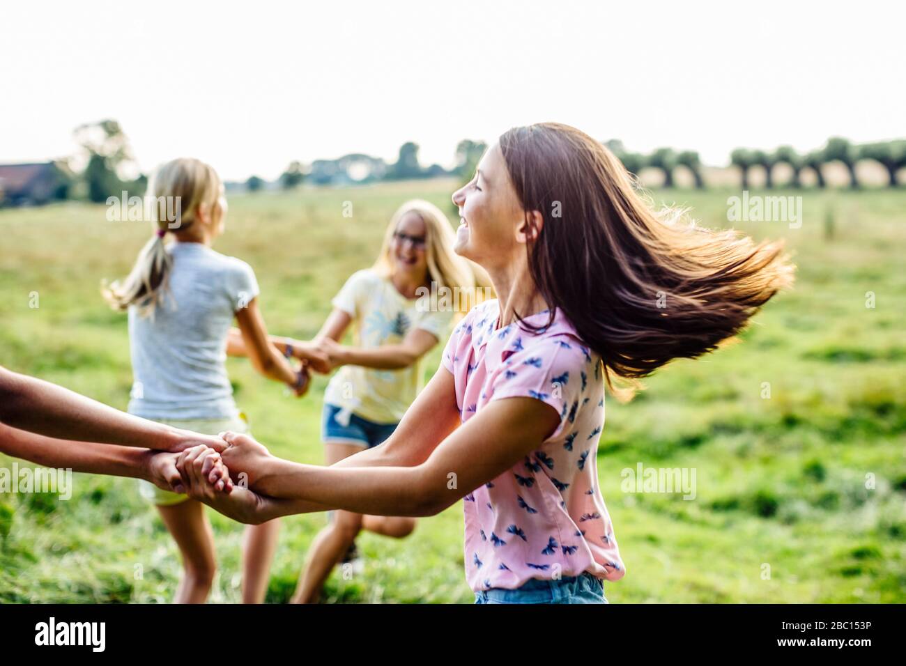Happy girls dancing on a field together Stock Photo - Alamy