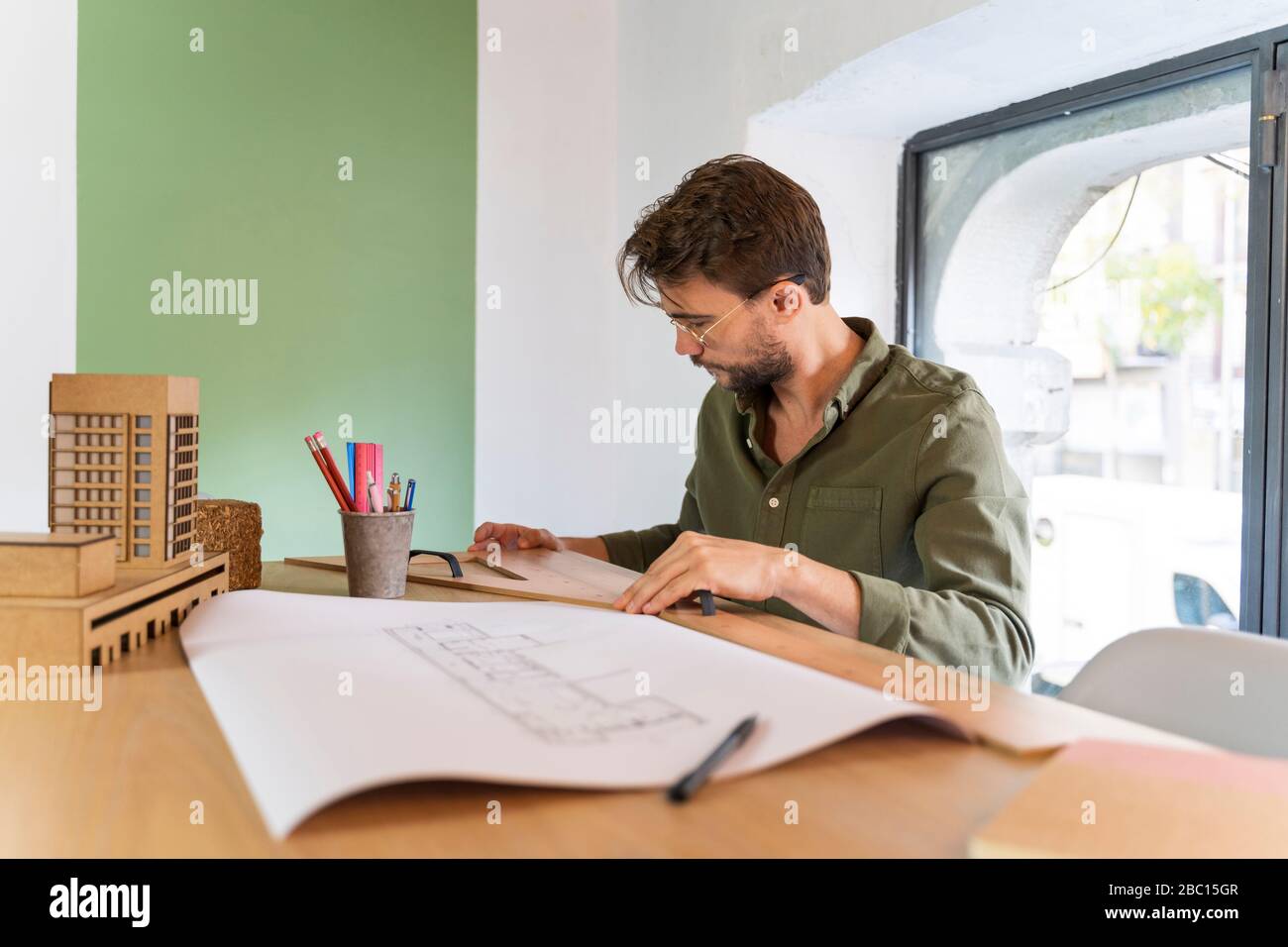 Man working on architectural model and plan on desk in office Stock ...