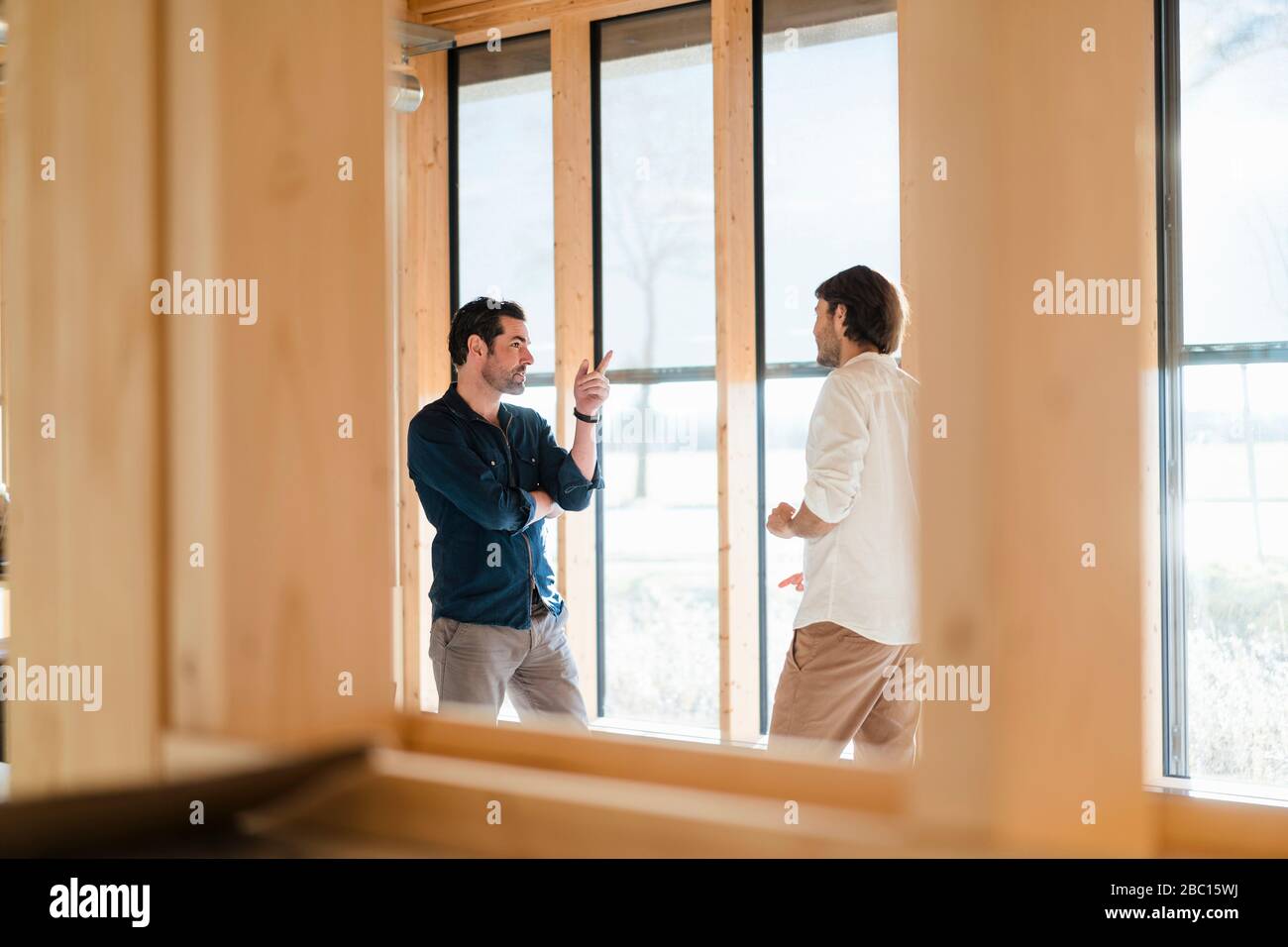 Two businessmen talking at the window in wooden open-plan office Stock ...