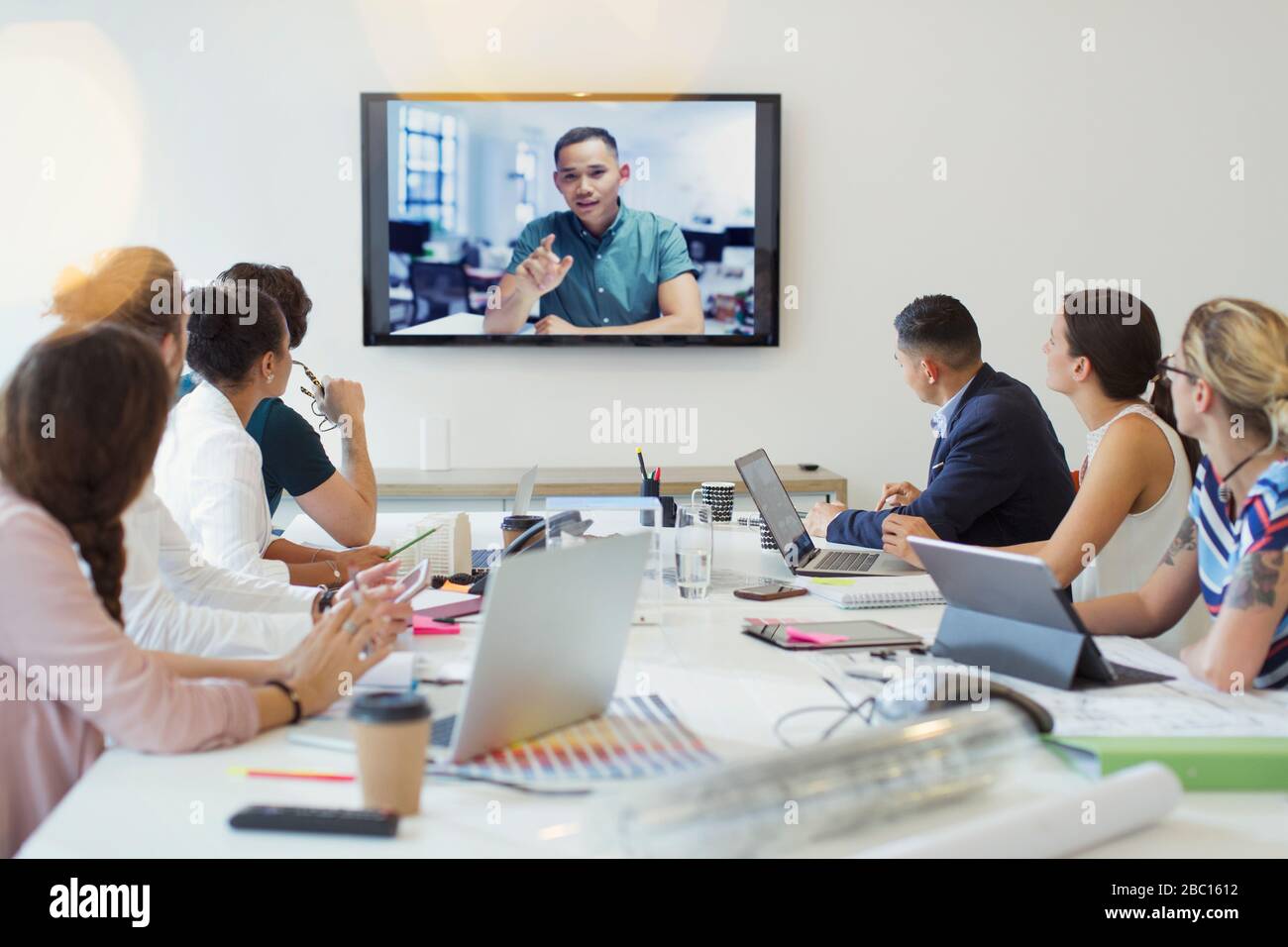 Designers video conferencing with colleague in conference room meeting ...