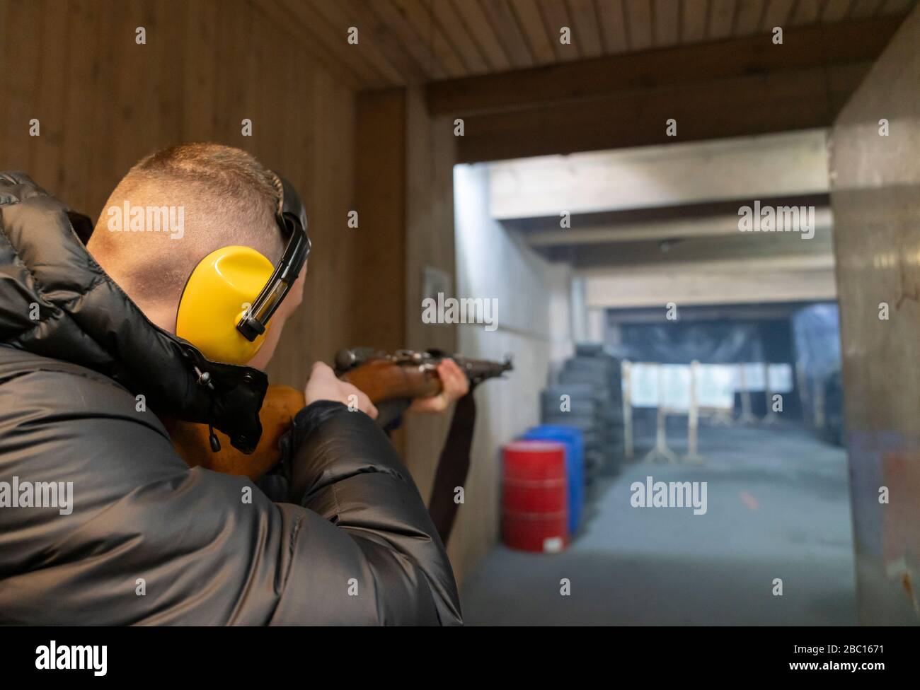 Young man aiming with a gun in shooting range Stock Photo - Alamy