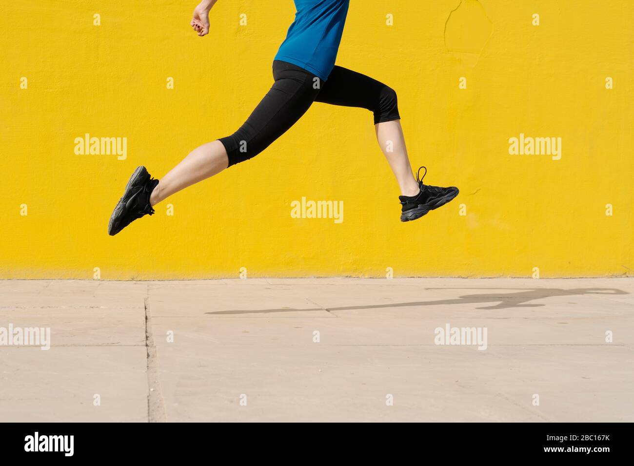 Young woman jogging in front of a yellow wall Stock Photo - Alamy