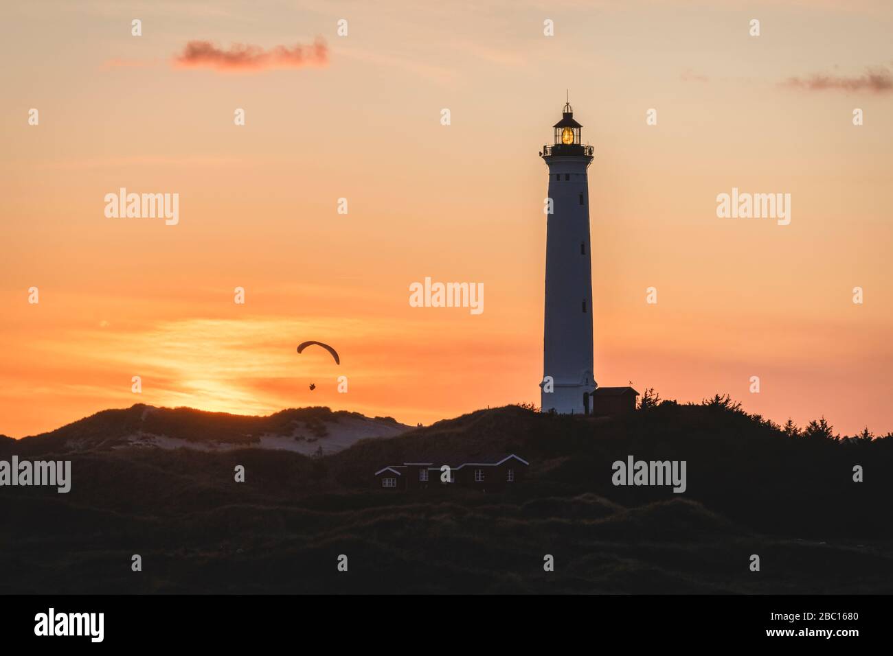 Denmark, Hvide Sande, Lighthouse standing against moody sky at dusk ...