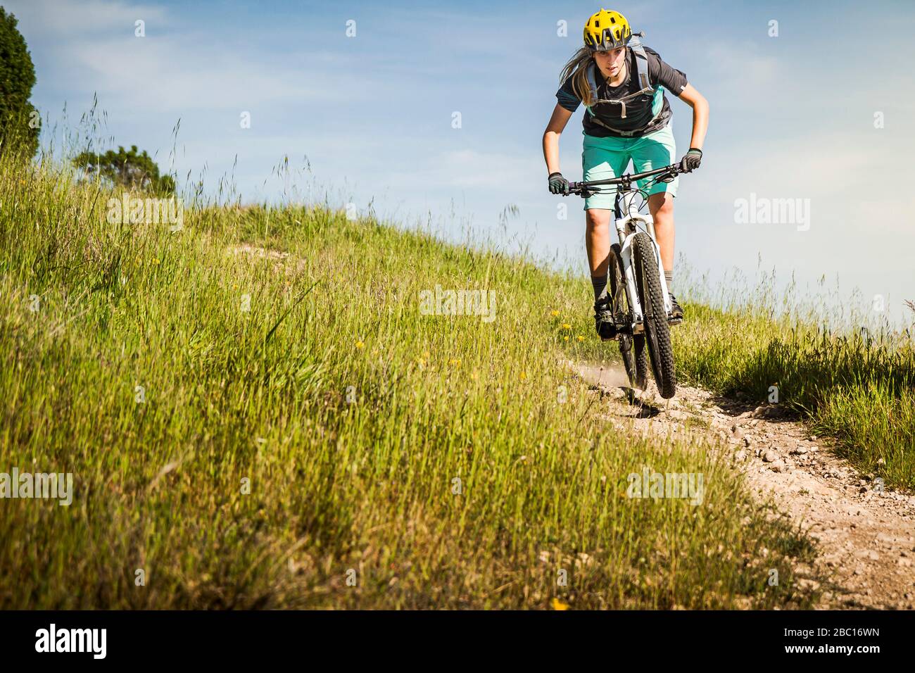 Woman on mountain bike riding down trail in front of blue sky, Santa ...